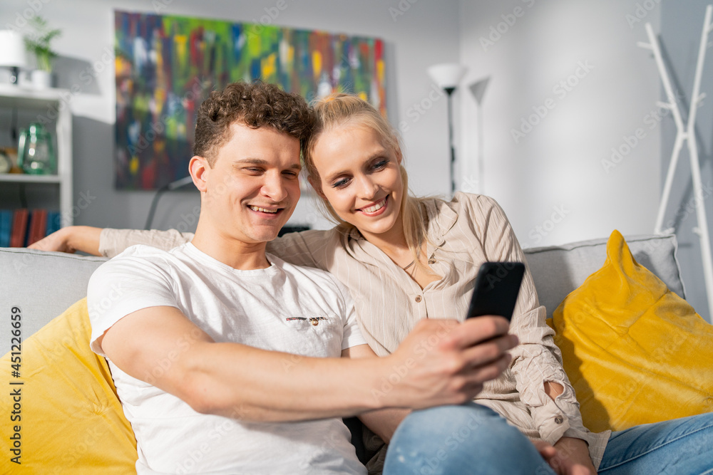 Two wonderful smiling cheerful people spend the afternoon on the sofa ...