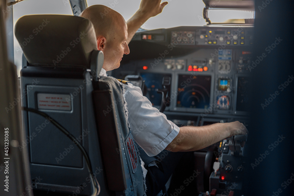 Focused professional pilot sitting in an airplane cabin, ready for ...
