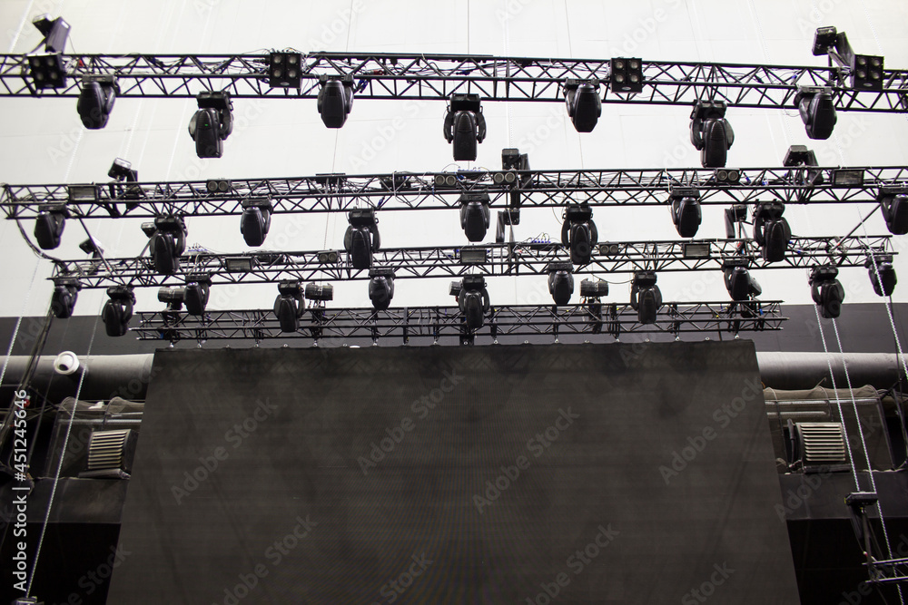 Moving head spotlight devices are clamped on a rigging steel trusses ...