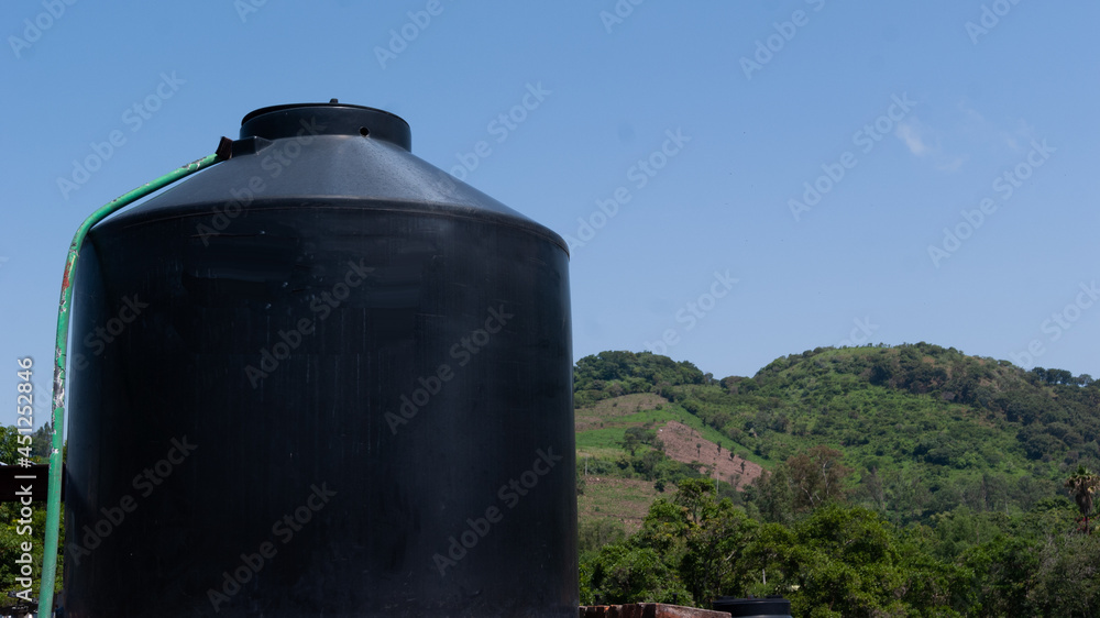 tinaco de agua negro en azotea de casa rural con cerros al fondo Stock ...