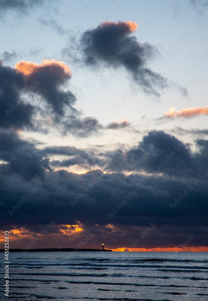 Foto de Lighthouse shining in the distance with brooding clouds ...