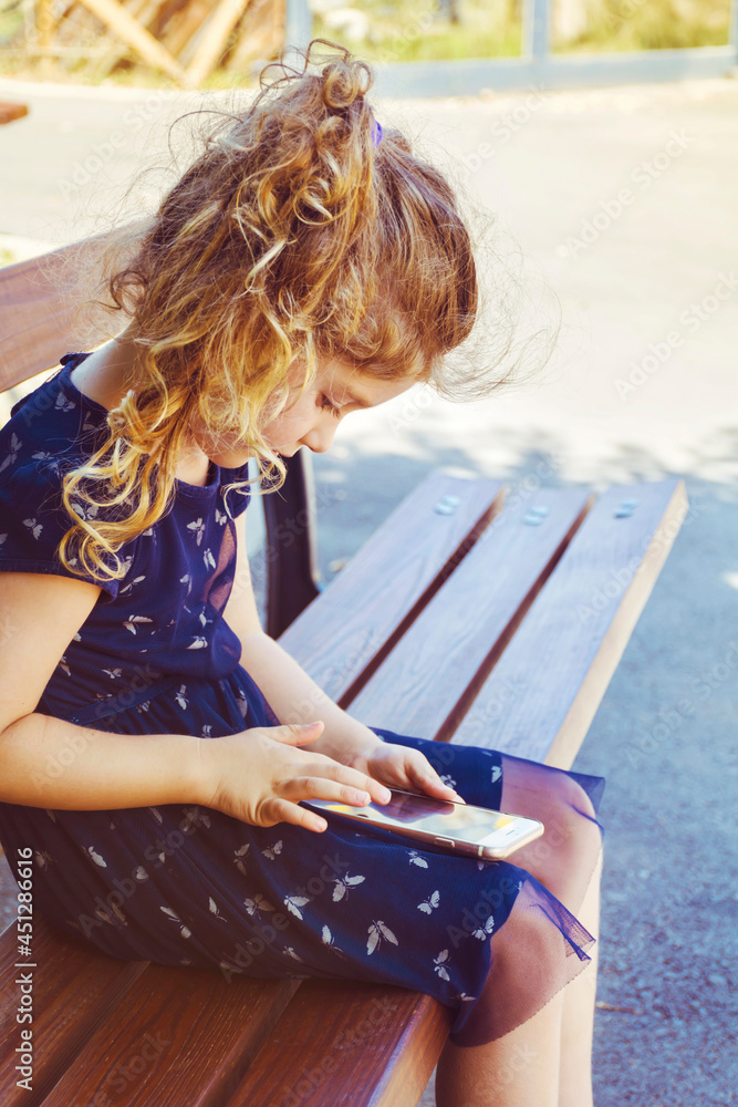 Toddler Girl Sitting Hunched Over on a Bench Playing with Mobile Phone ...