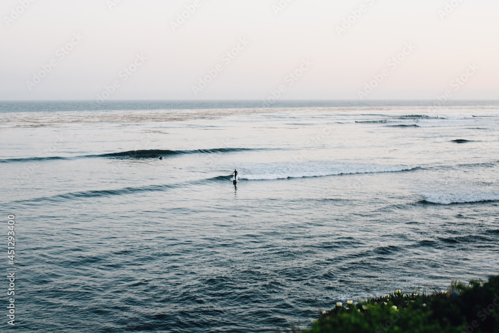 Lone surfer out in the ocean, lots of negative space and open areas ...