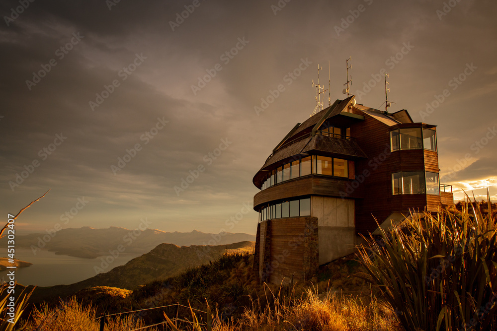 High on a hilltop, the gondola building is lit up in the golden hour ...