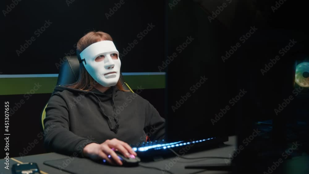 The hacker girl at the computer removes the mask from her face and ...