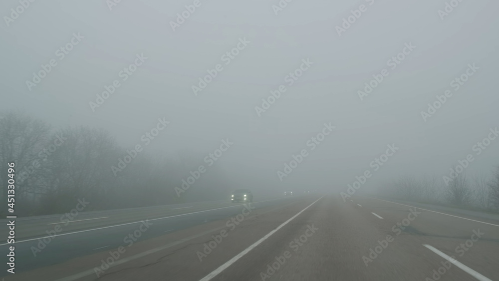 Cars move on foggy road, view through windshield in daytime. Cars pass ...