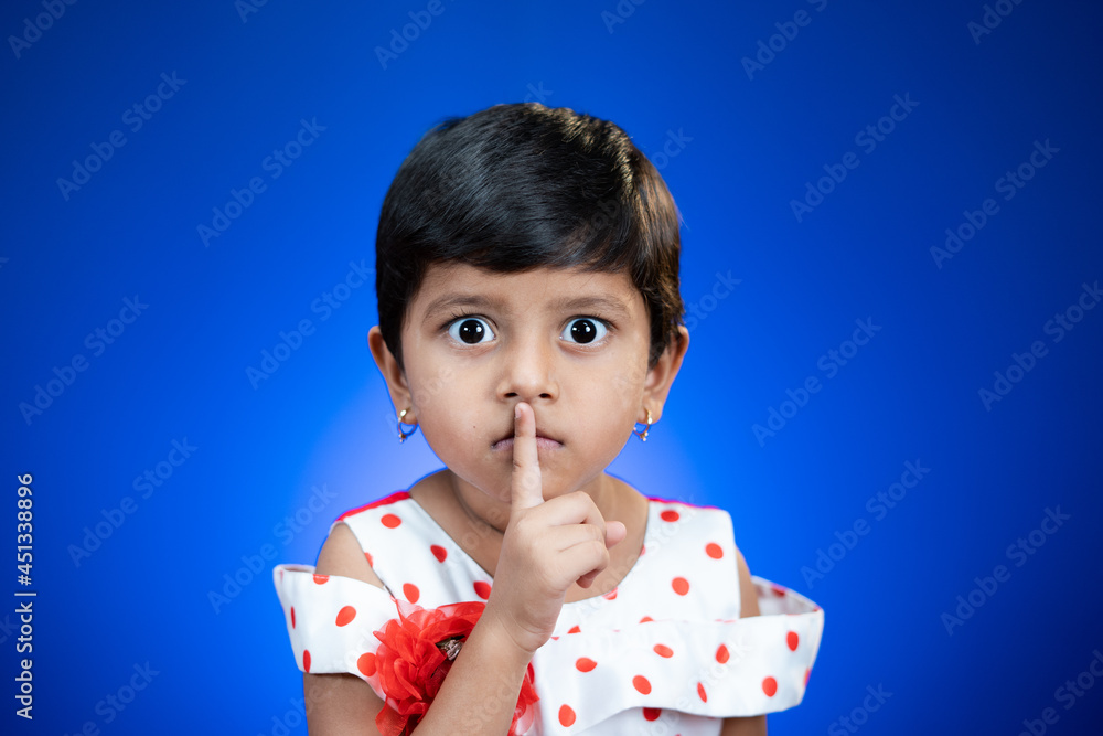 Cute girl kid saying keep silence quite by placing finger on mouth on ...