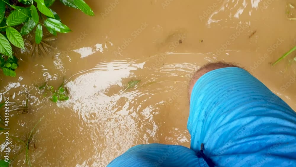 A person walking barefoot through brown muddy flood water after ...