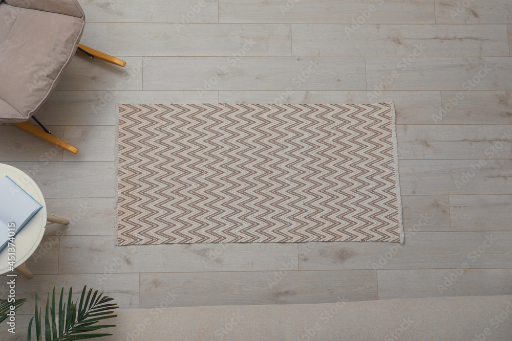 Light carpet with geometric pattern on wooden floor in room, top view ...
