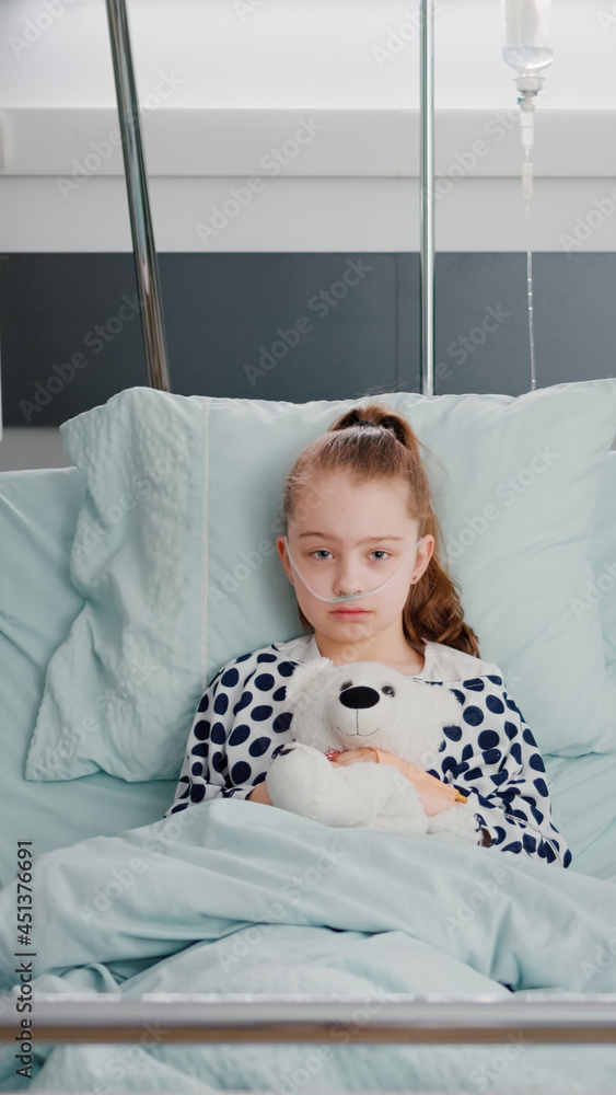 Portrait of hospitalized sick girl child patient holding teddy bear ...