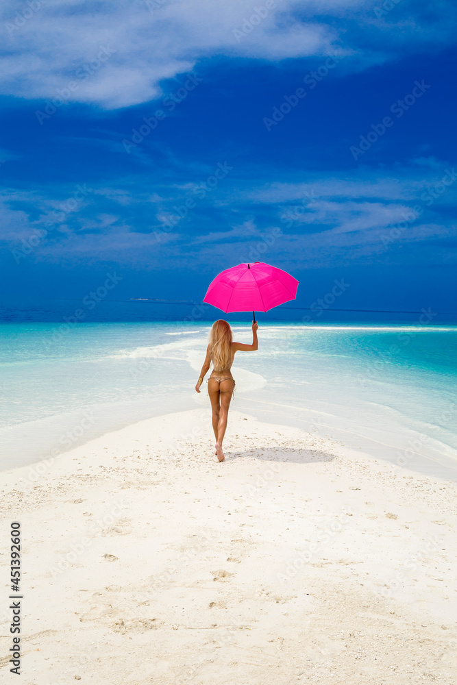 Beautiful sexy tanned woman bikini model with pink umbrella on Maldives island. Young glamour ...