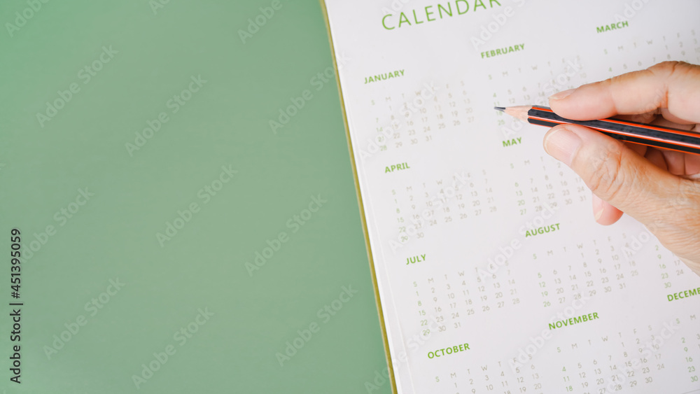 hand holding pencil with blurred yearly calendar for planning work ...