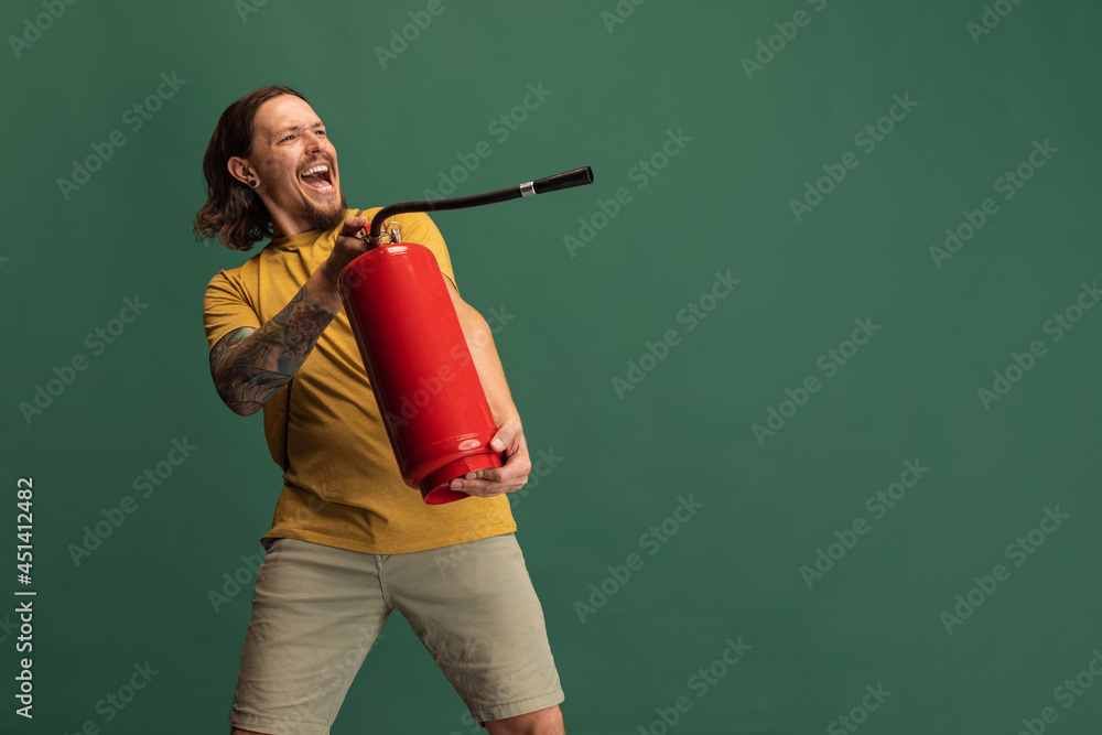 Comic portrait of young man with fire extinguisher having fun isolated ...