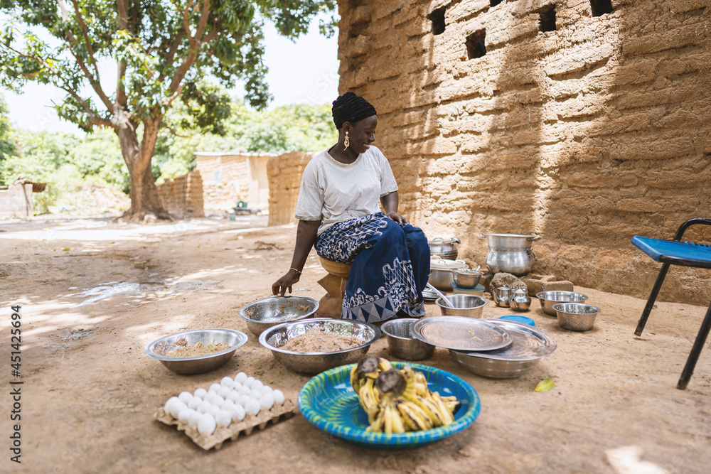 Content young African housewife sitting in the middle of pots and pans ...