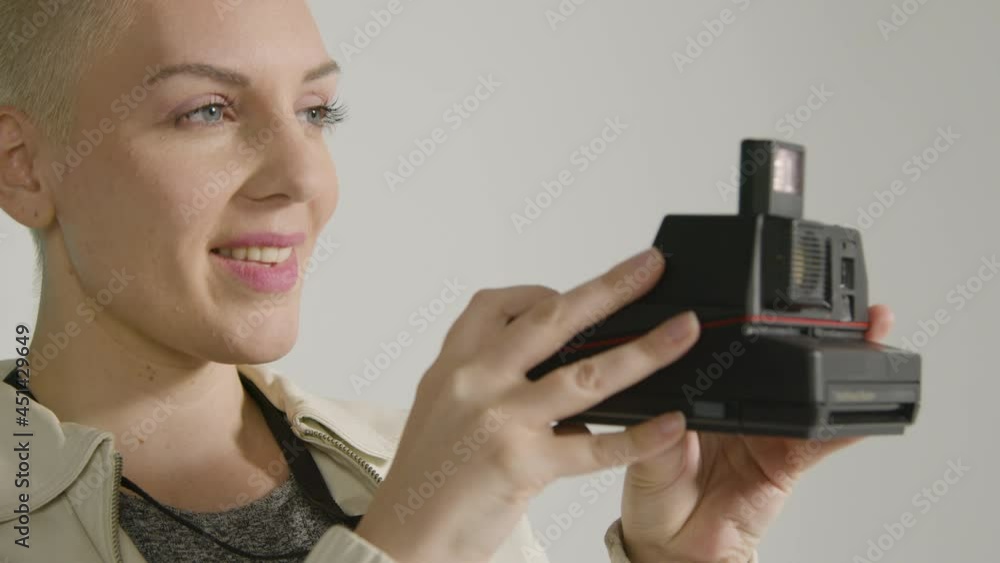 Side view of a female photographer posing with instant film camera 01 ...