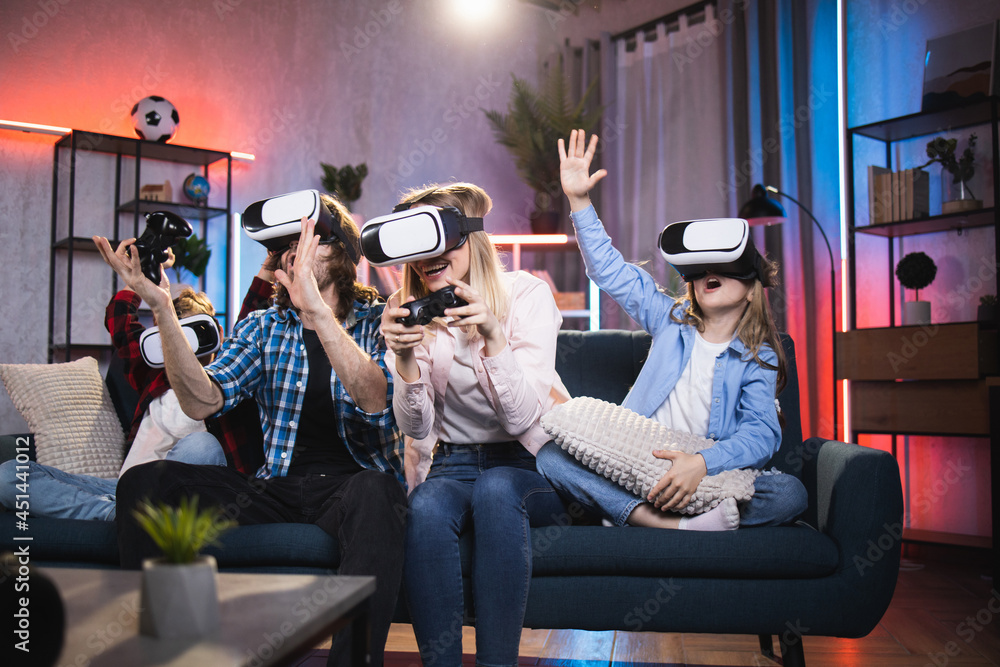 Cheerful kids with their young parents wearing 3D goggles while playing ...