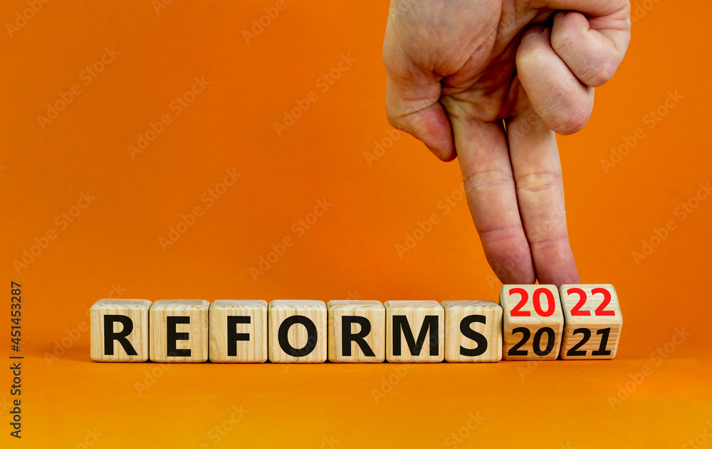 2022 reforms new year symbol. Businessman turns a wooden cube and ...