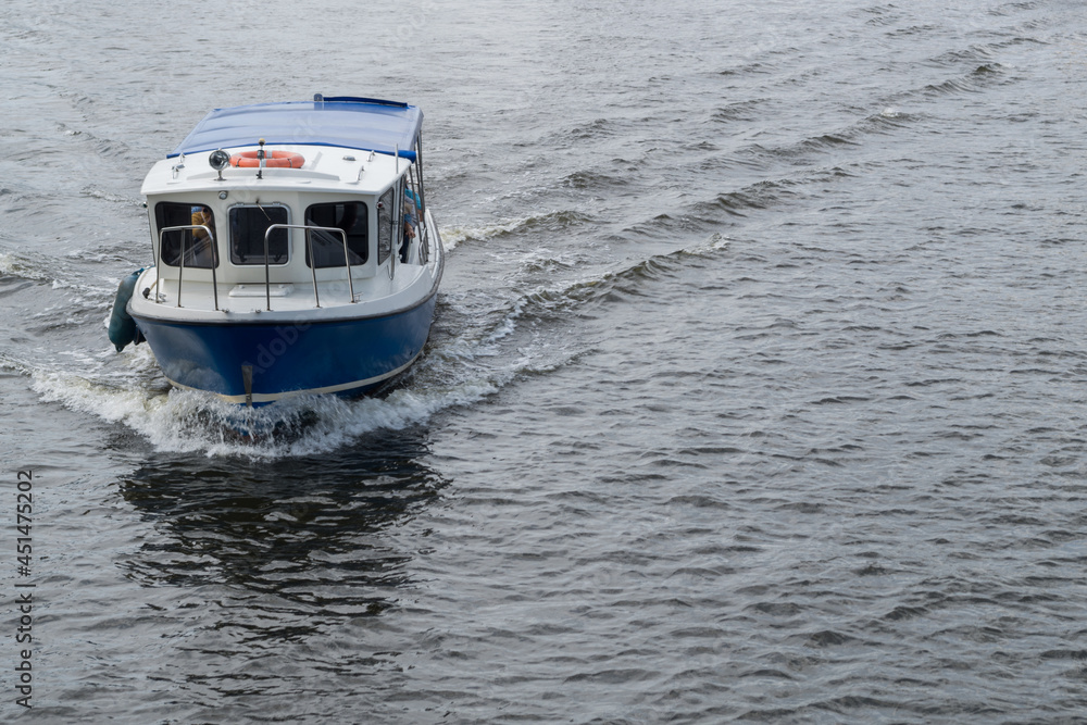 Pleasure boat with streamlined blue side, white cabin, metal rails in ...