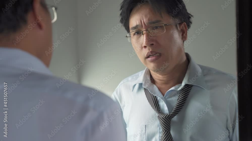 Unemployed Asian man standing in front of mirror screaming and blame ...