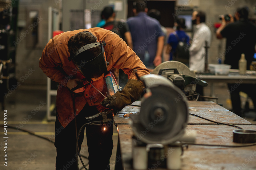 Hombre soldando en un taller con protección para el rostro y sus cuerpo ...