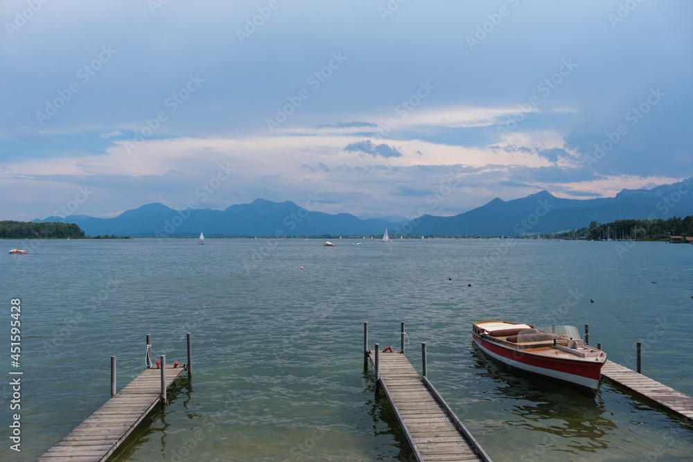 Ein kleines Boot liegt an einem Steg am Ufer von einem See (Chiemsee ...