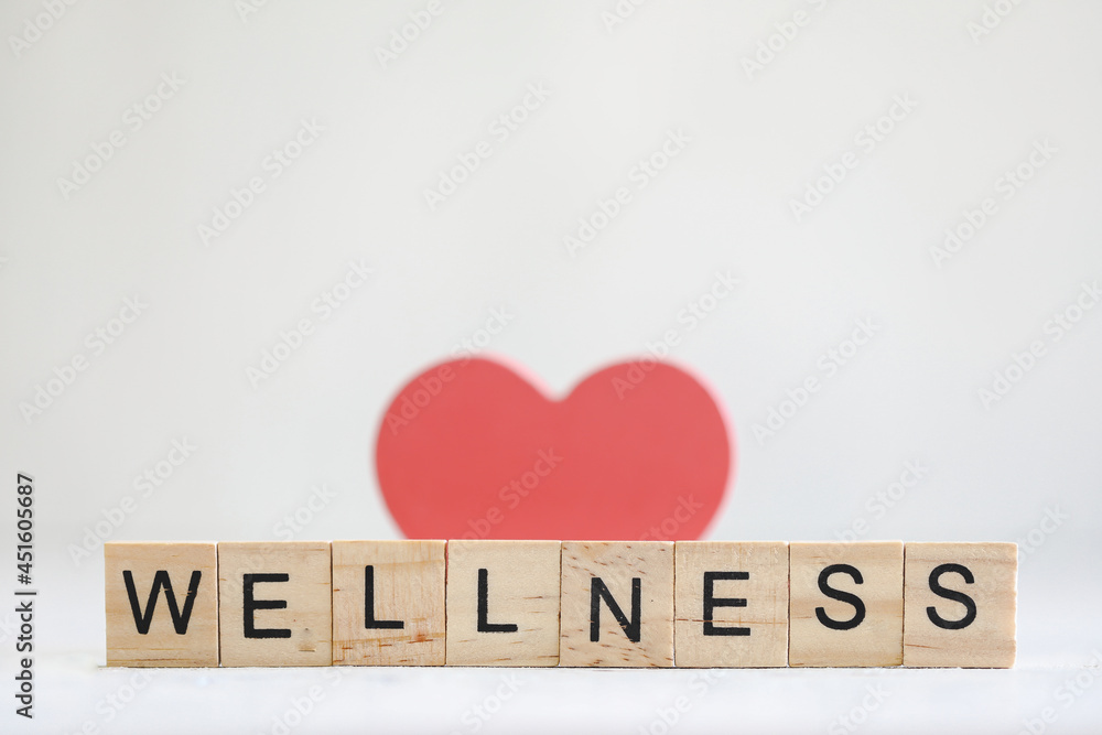 WELLNESS text in wooden block letters with red heart on plain white ...