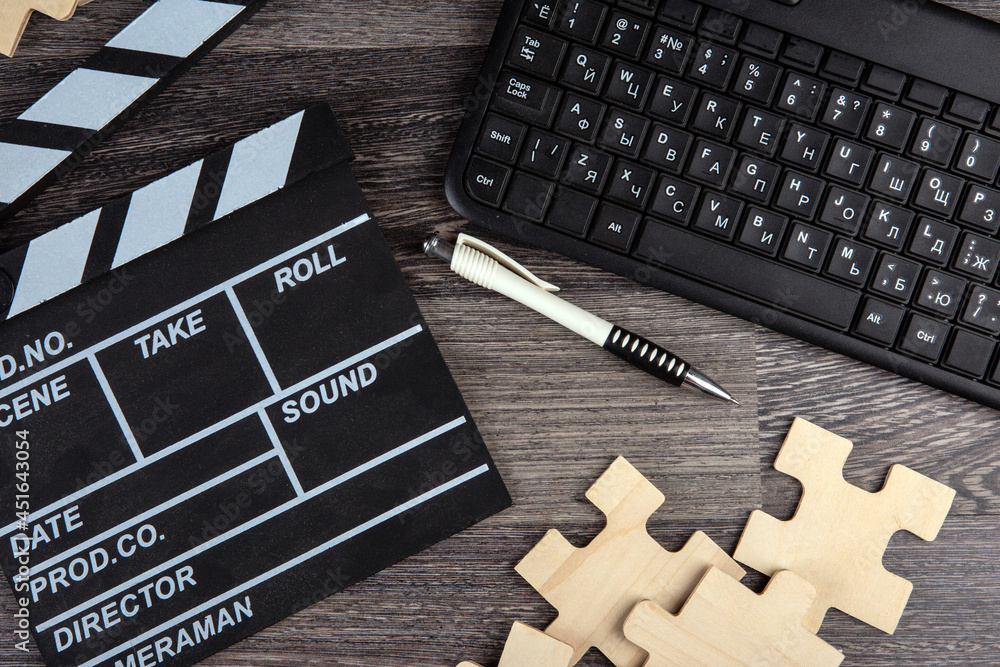 cinematic clapper, pc keyboard, pen and puzzle pieces on a table Stock ...