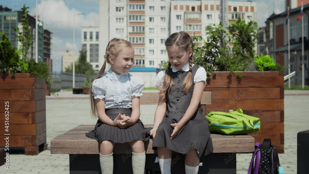 Portrait of two girls in school uniform at schoolyard. They talking and ...