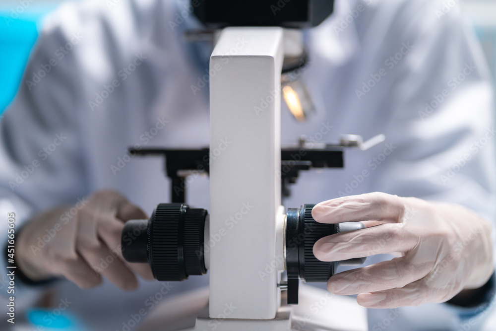 scientist looking through scientific microscope lense in laboratory ...
