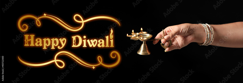 Female hand with diya lamp and text HAPPY DIWALI on dark background ...