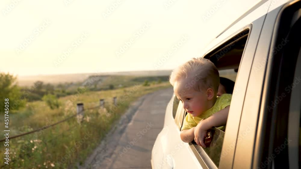 Teen boy looking out the car window and waving his hand. Family travel ...
