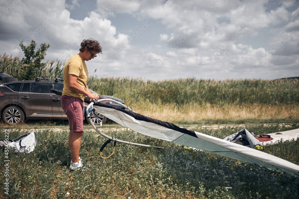 Windsurfer and camper packing and unpacking from a car's roof rack in ...