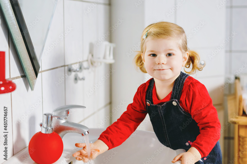 Cute little toddler girl washing hands with soap and water in bathroom ...