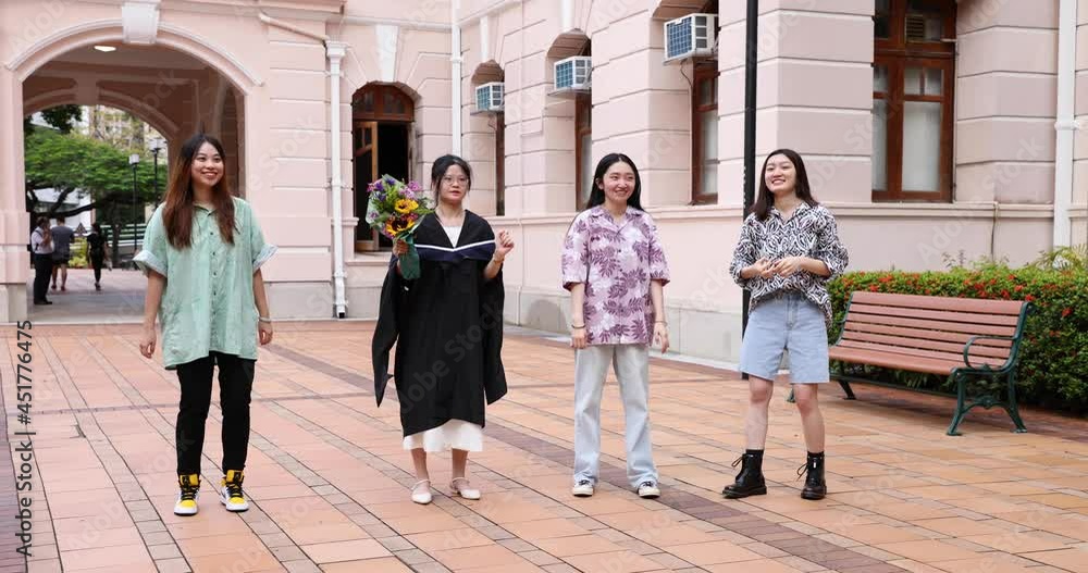 female graduate students in academic dress and friends jump in front of ...