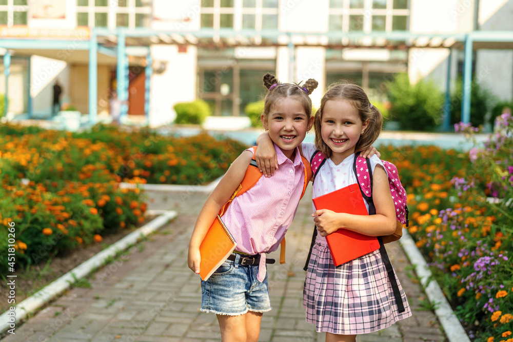 Two girls, elementary school students with backpacks, walking down ...