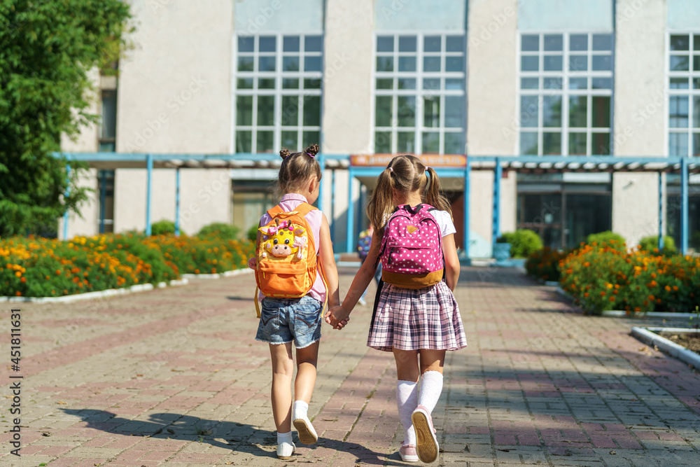 Two girls, elementary school students with backpacks, walking down ...