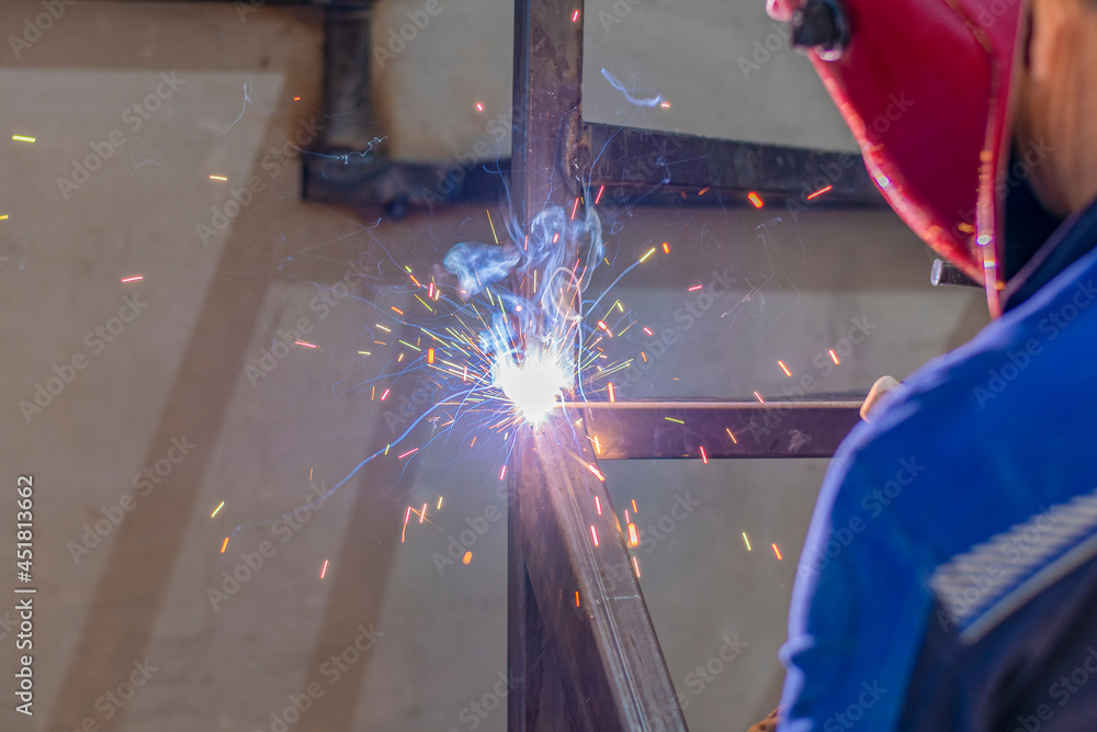 Working male welder with the help of a welding machine assembles the ...