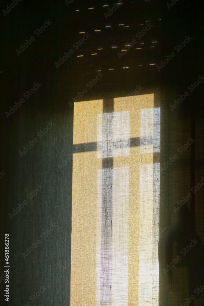 Vertical window with bars and its shadow on the curtain inside a house ...