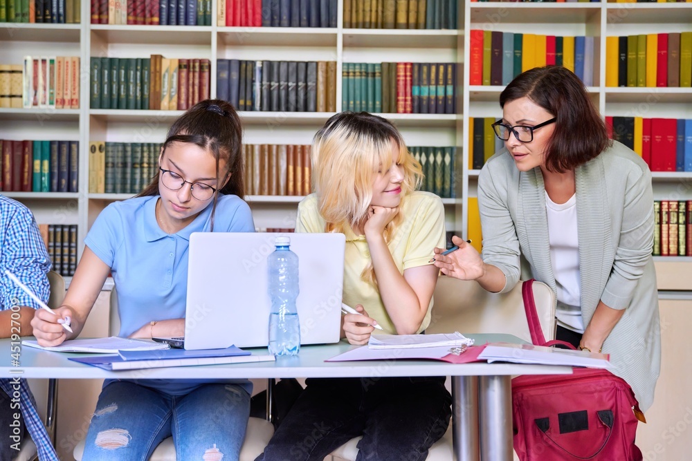 Girls teenage students studying in library with teacher mentor Stock ...