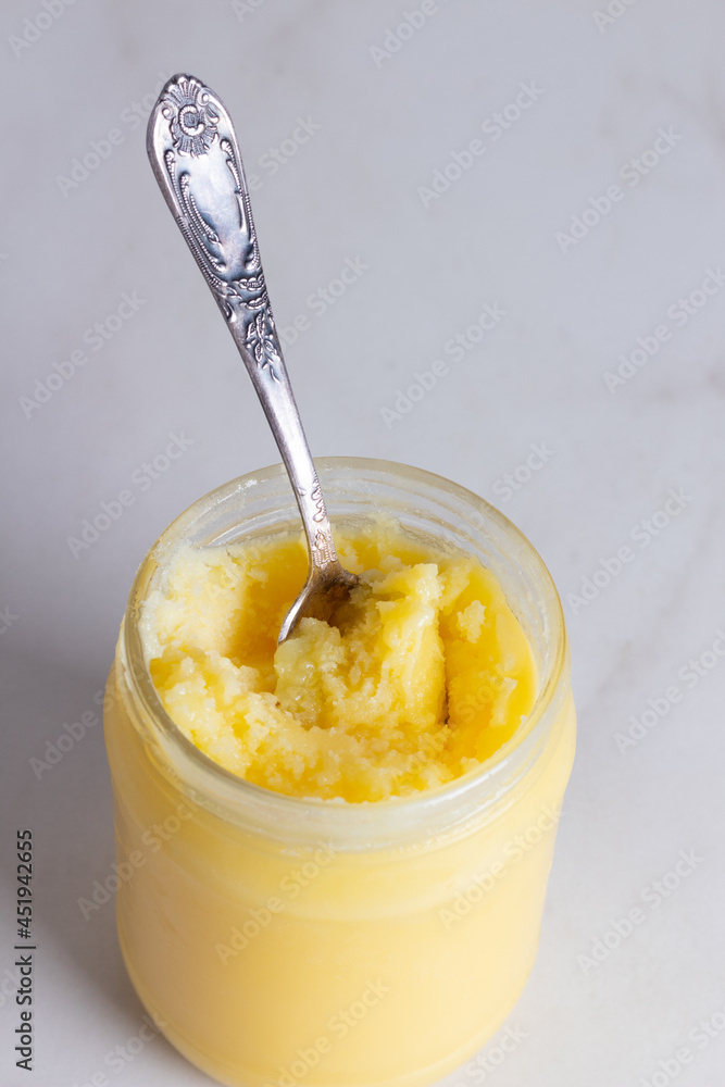 Indian ghee clarified butter desi in glass jar on neutral grey ...
