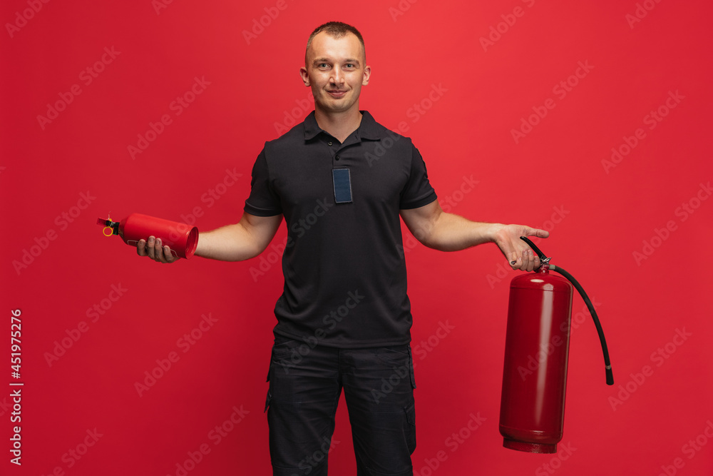 Fire safety. Portrait of young smiling man with extinguishers posing ...