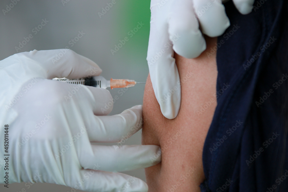 Close up nurse making a vaccination in the shoulder of the patient ...