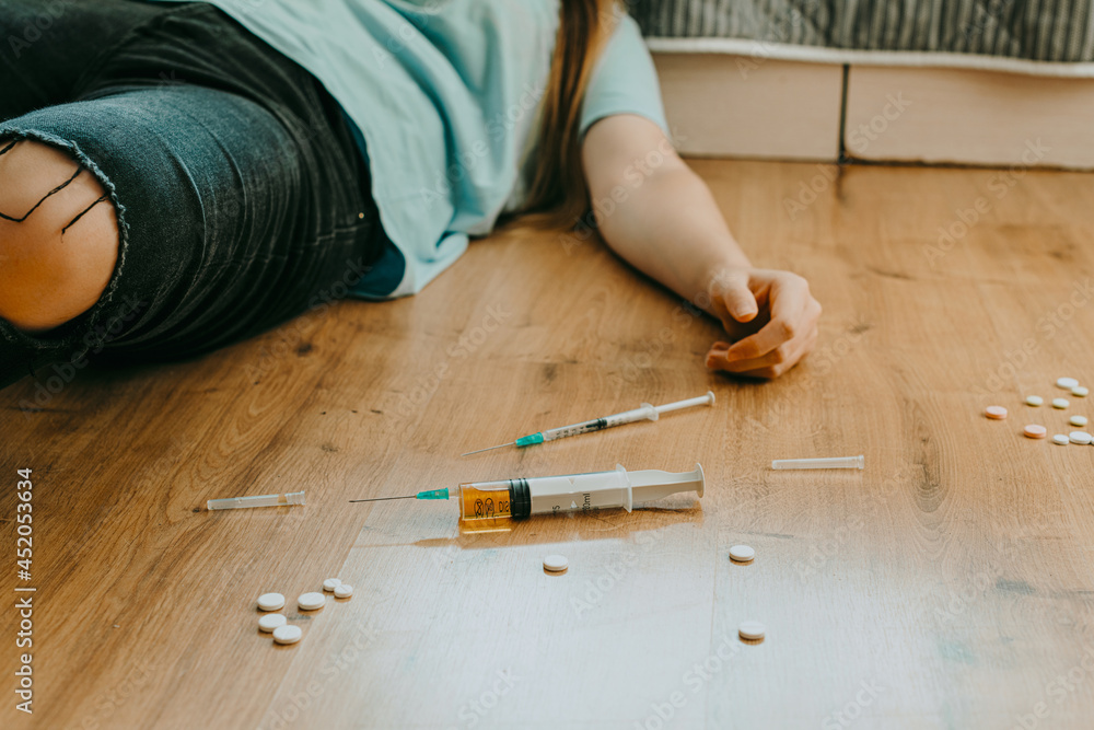Addict woman after drugs overdose. Syringe and drugs on the floor ...