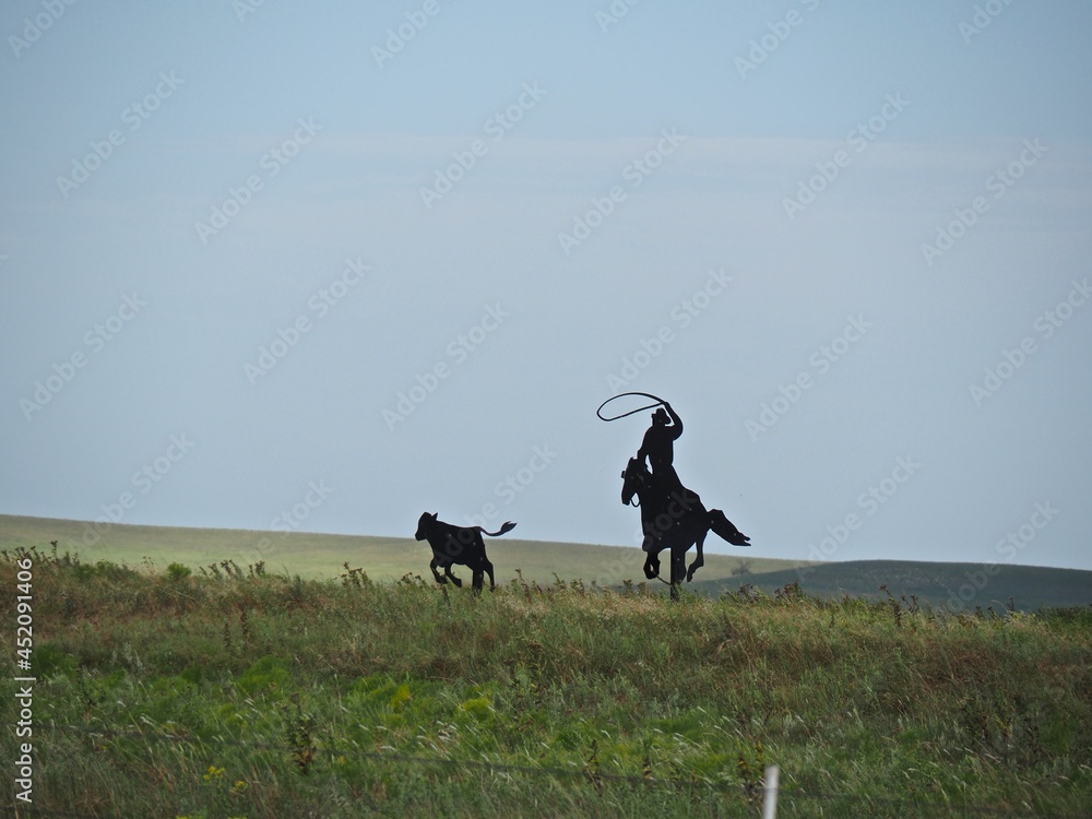 Metal sculpture of cowboy lassoing a cow in the Flint Hills of Kansas ...