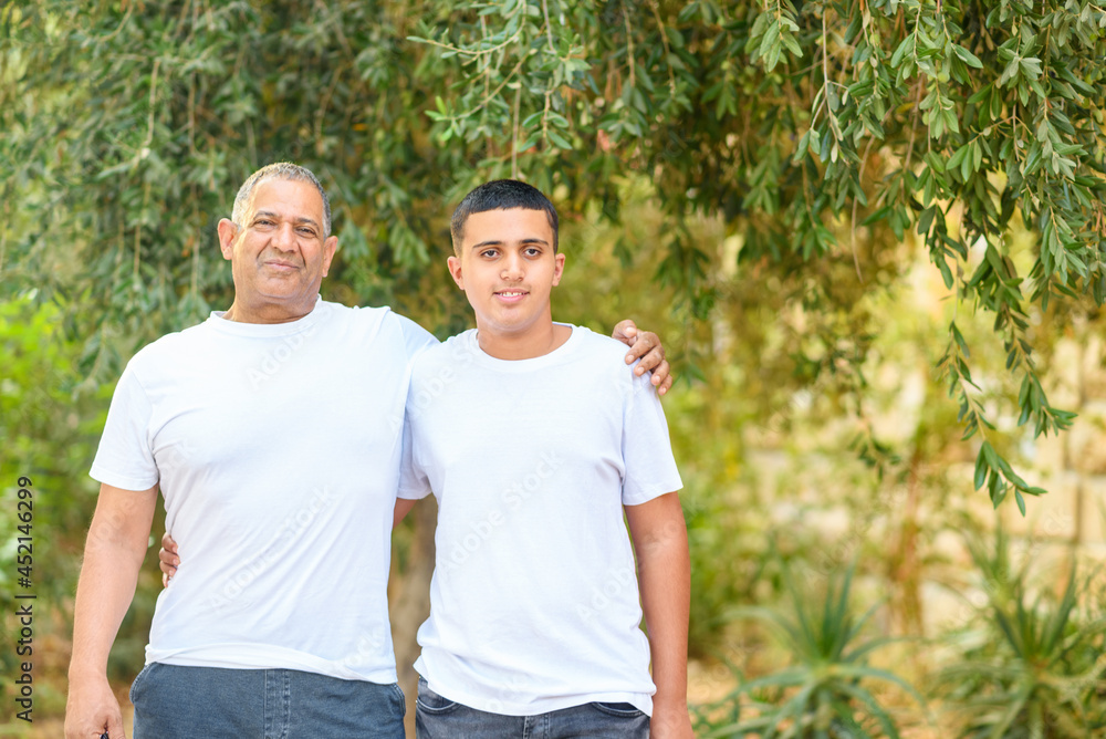 Teenager son and senior father standing outdoors. Old father hugging ...