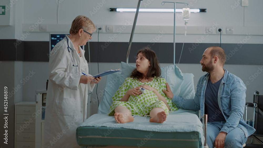 Hospital ward doctor consulting pregnant woman in bed for childbirth ...