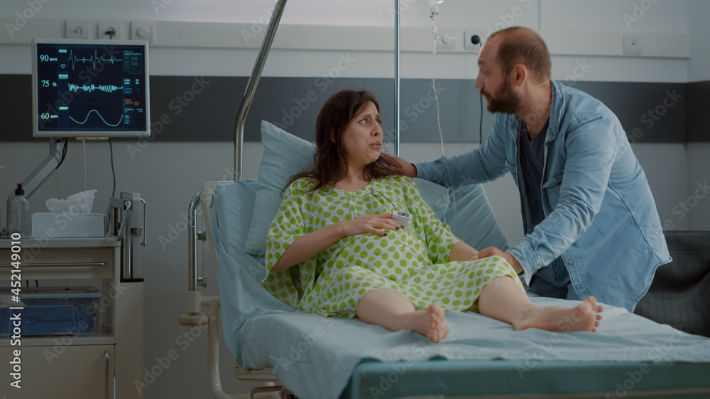 Young woman going into labor in hospital ward sitting with husband ...