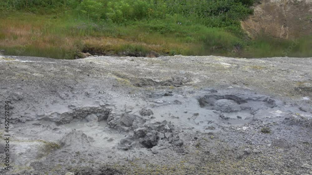 Natural hot springs. Gray liquid boils in the holes on the ground ...