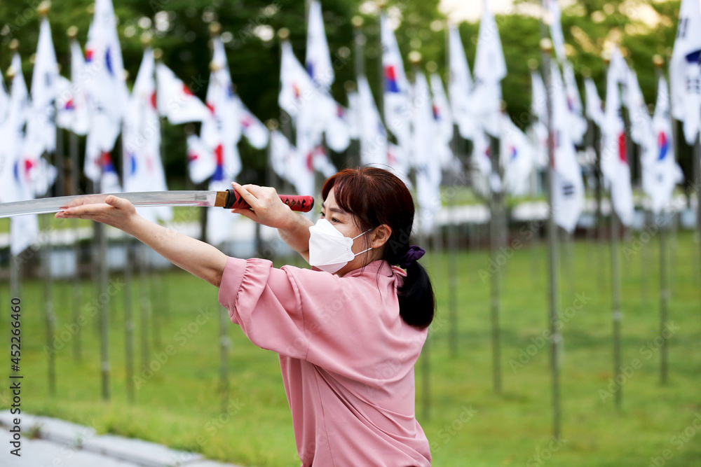 Korean woman practicing kendo in a hi-dong kendo pose with a sword ...