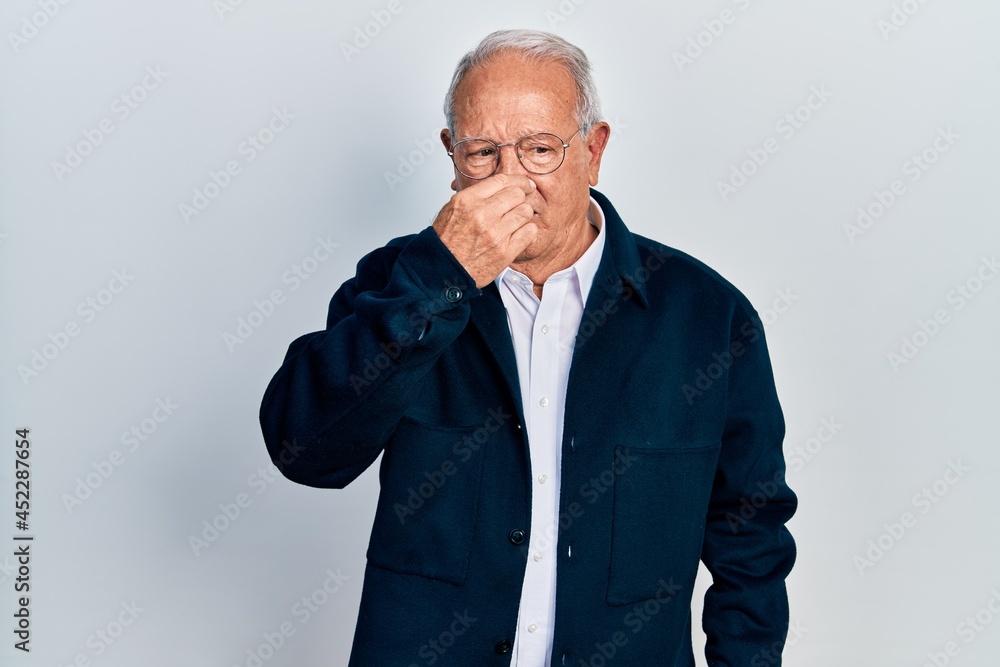 Senior man with grey hair wearing casual style and glasses smelling ...